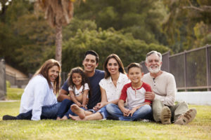 Three generation Hispanic family sitting on the grass in the park ...